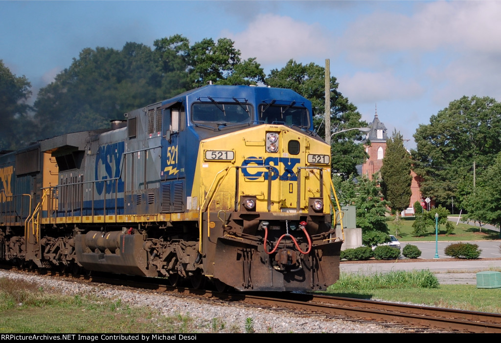 CSX AC-4000CW #521 is about to cross Main St. with an eastbound grain train